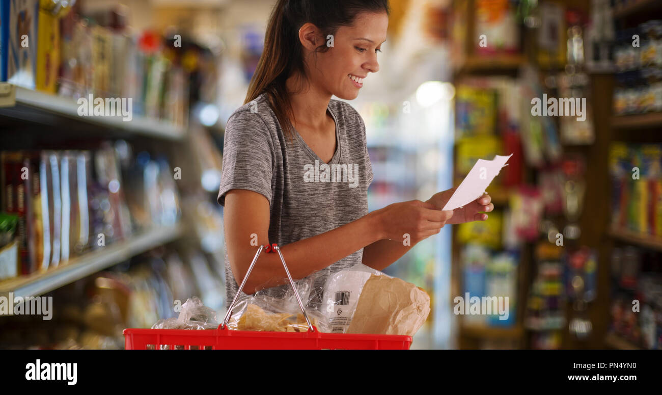Young wife or mother with shopping list looking for item in grocery ...