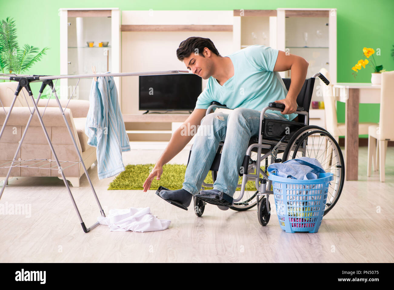 Disabled man on wheelchair doing laundry Stock Photo - Alamy