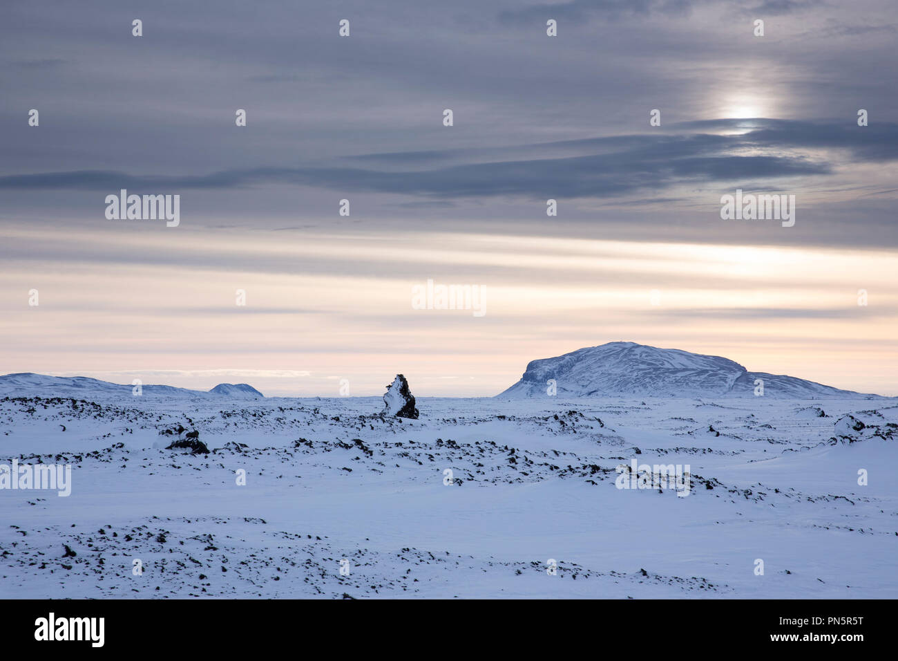 Wintry sun and clouds above snow-covered mountains and landscape of ...