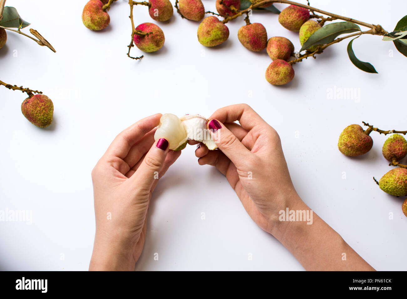 Female hands peeling lychee fruit on white Stock Photo - Alamy