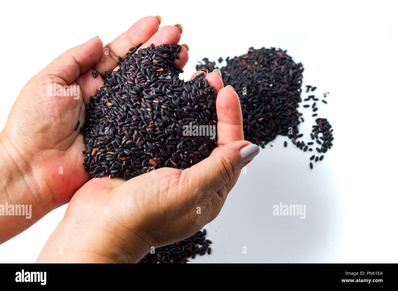 Female hands holding black rice grains isolated Stock Photo - Alamy