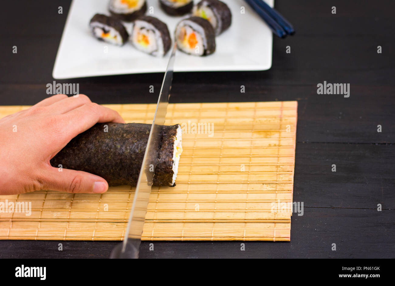 Hands cutting sushi roll hi-res stock photography and images - Alamy