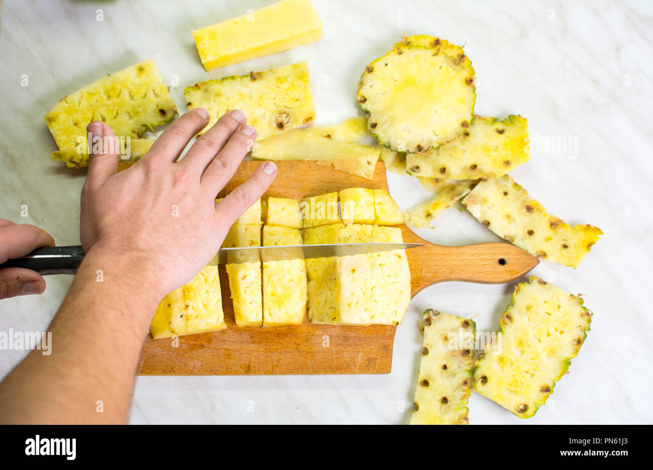 Male hands slicing pineapple fruit on a wooden board Stock Photo - Alamy