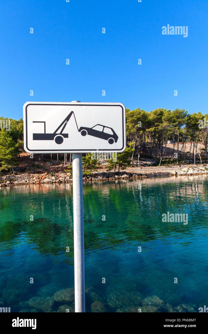 Car towing sign by the sea. Street sign of a car being removed in white ...