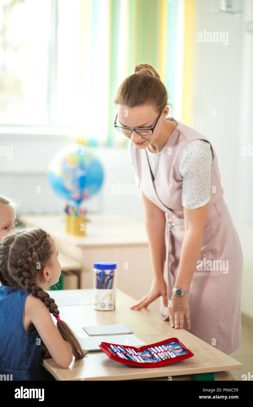 Teacher helping kids with their homework in classroom at school Stock ...