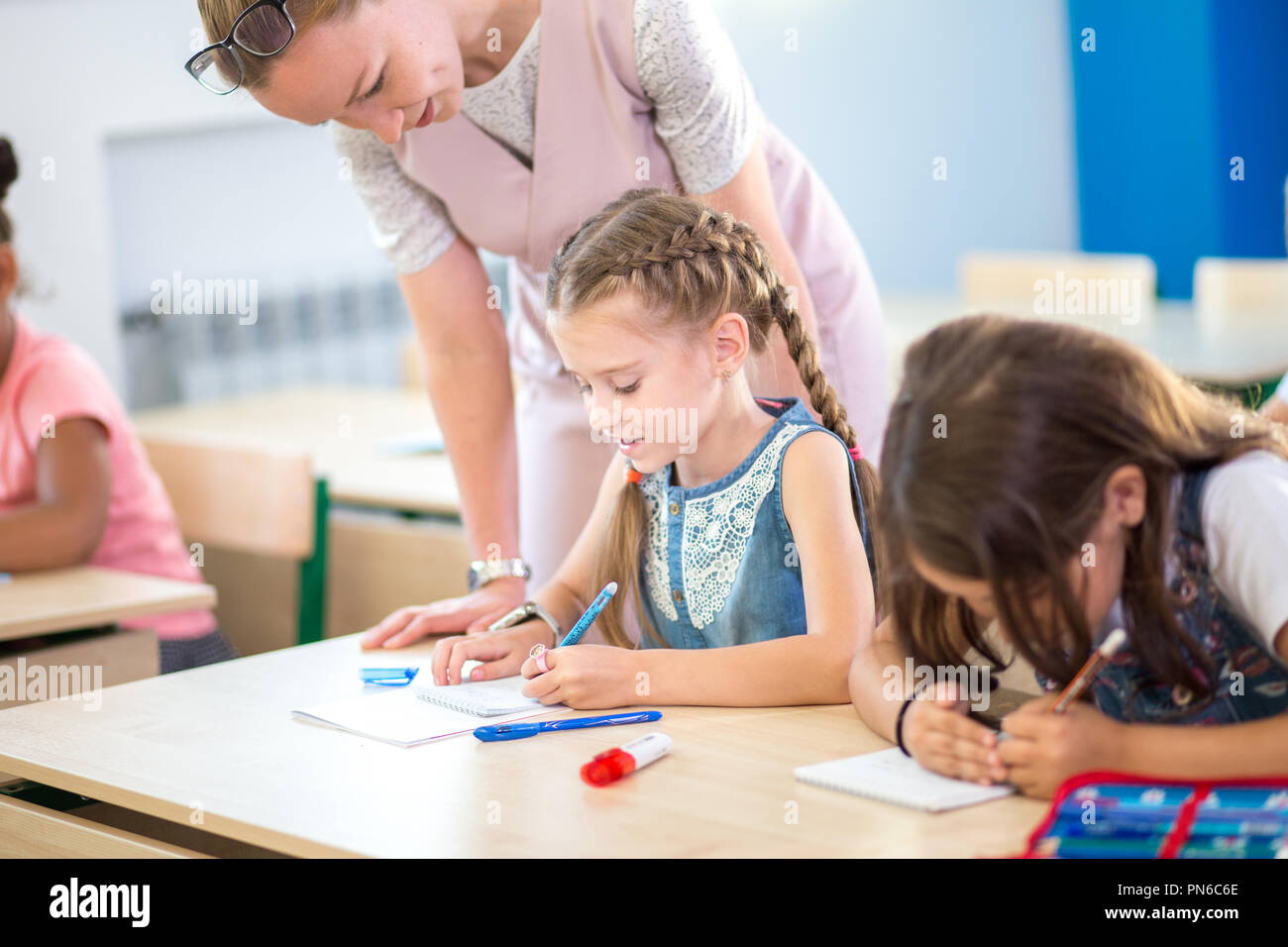 Teacher helping kids with their homework in classroom at school Stock ...