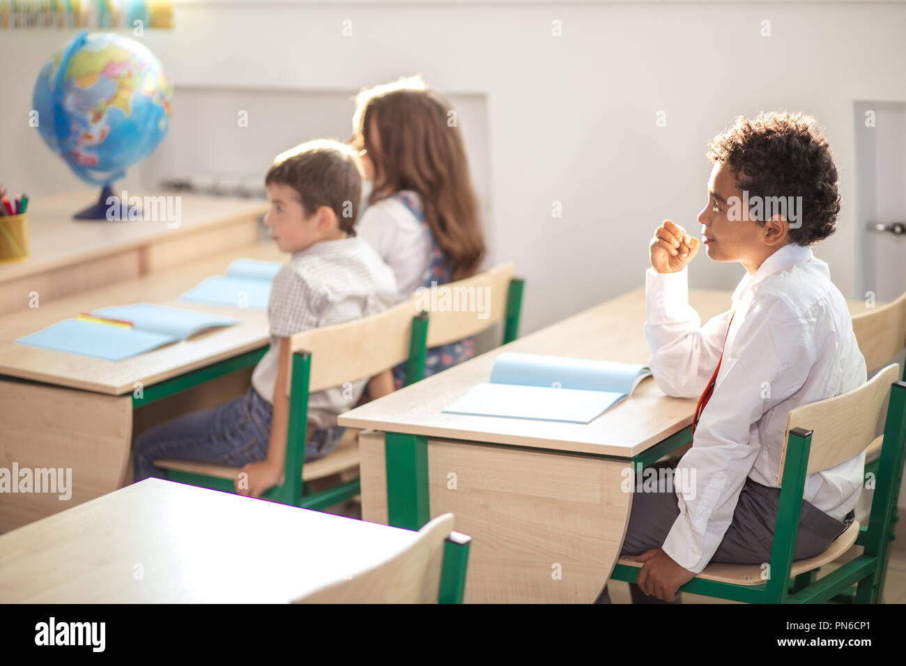 school boy sitting in desk and thinking while writing exam Stock Photo ...
