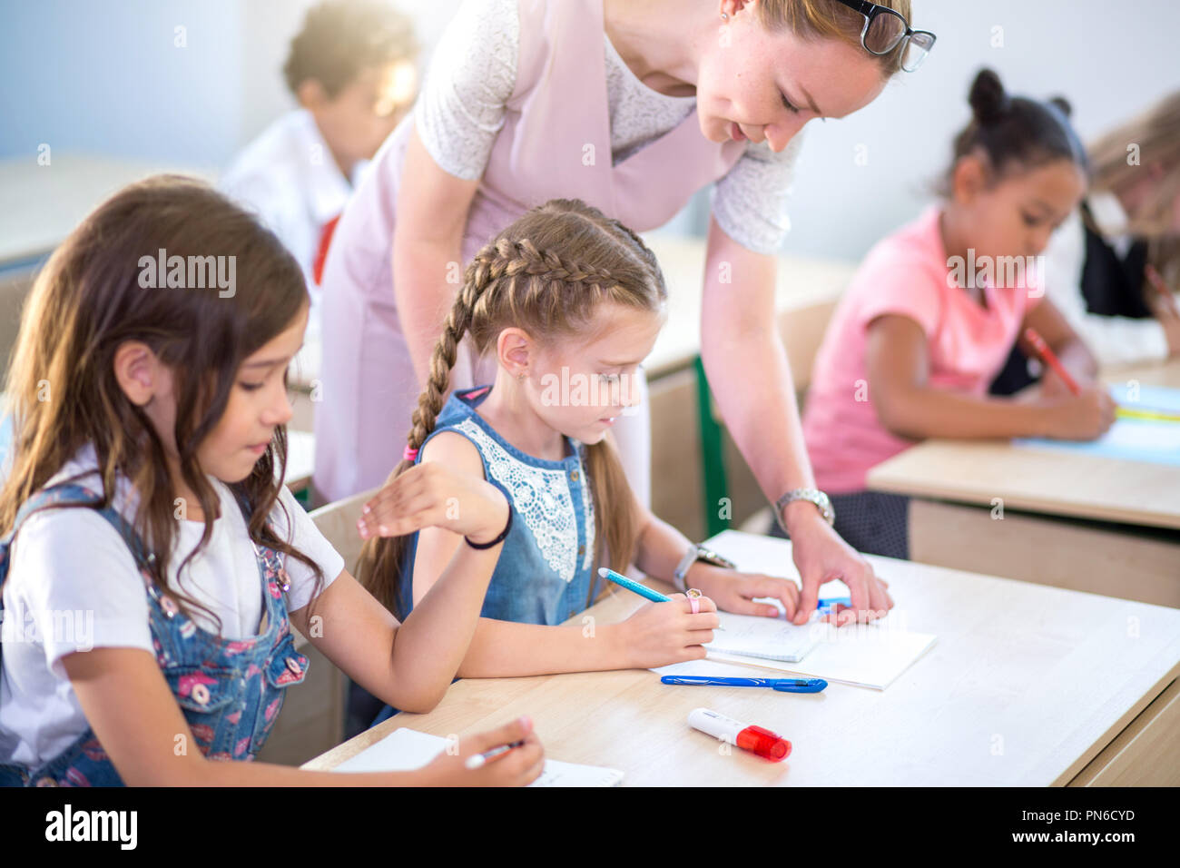 Teacher helping kids with their homework in classroom at school Stock ...