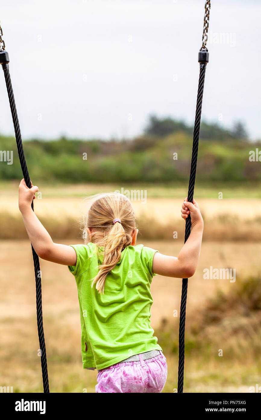 Little girl having fun standing on outdoor swing Stock Photo - Alamy