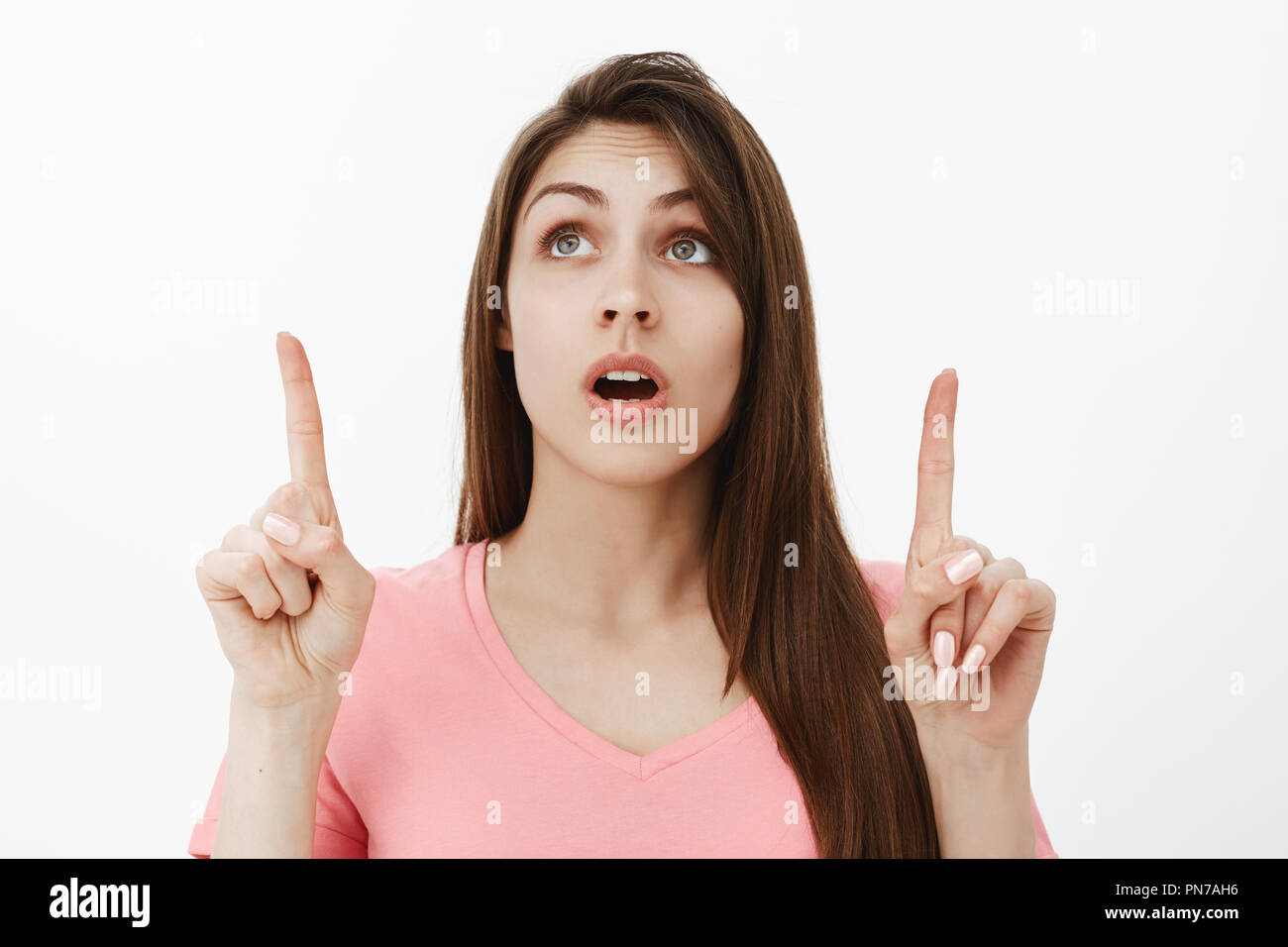 Studio shot of enthusiastic charming Caucasian female student in pink t ...