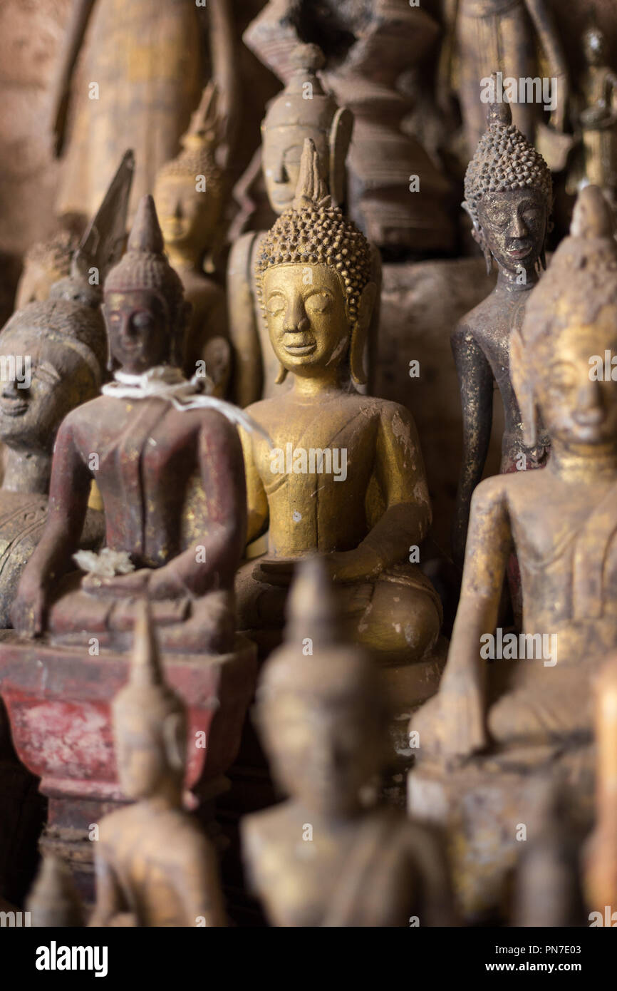 Close-up of many old and faded, golden and wooden Buddha statues inside ...
