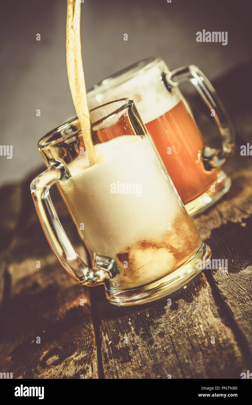 Pouring beer in glasses on rustic background Stock Photo - Alamy