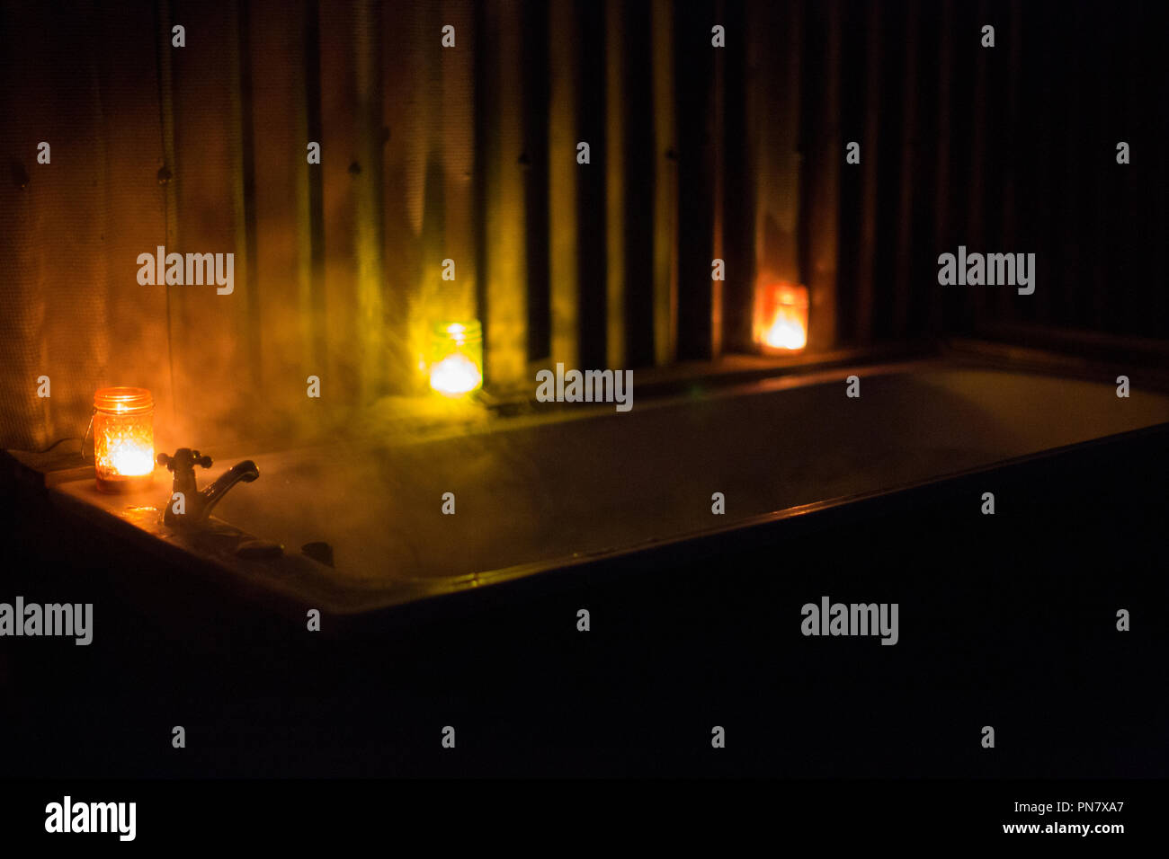 Steam rising off an outdoor bath in the candle light Stock Photo - Alamy