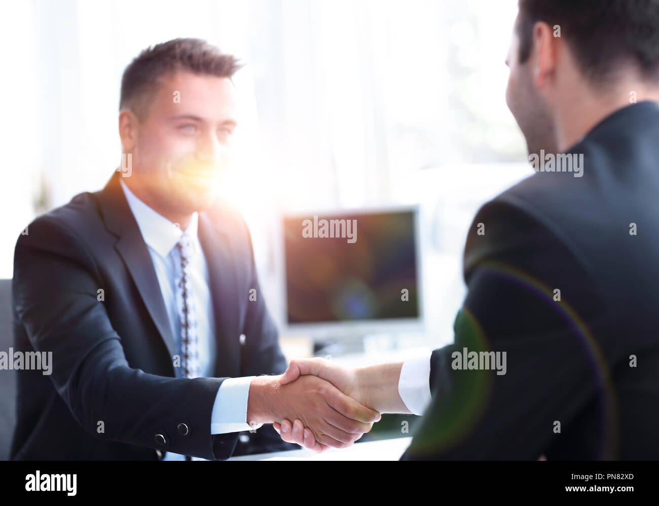 handshake of business partners sitting at a Desk Stock Photo - Alamy