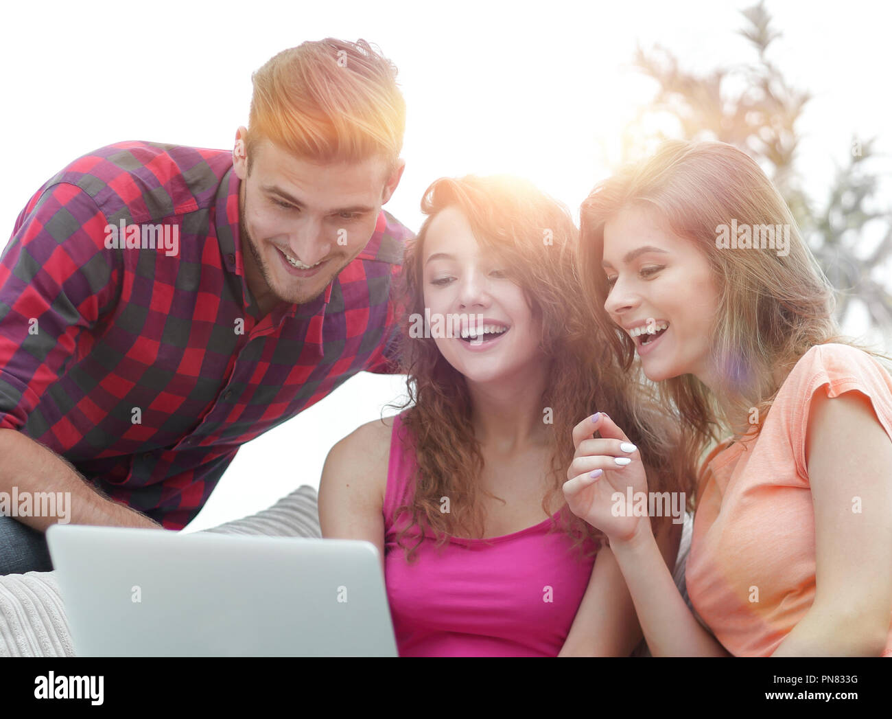 group of students looking at a laptop screen,sitting on the couch Stock ...