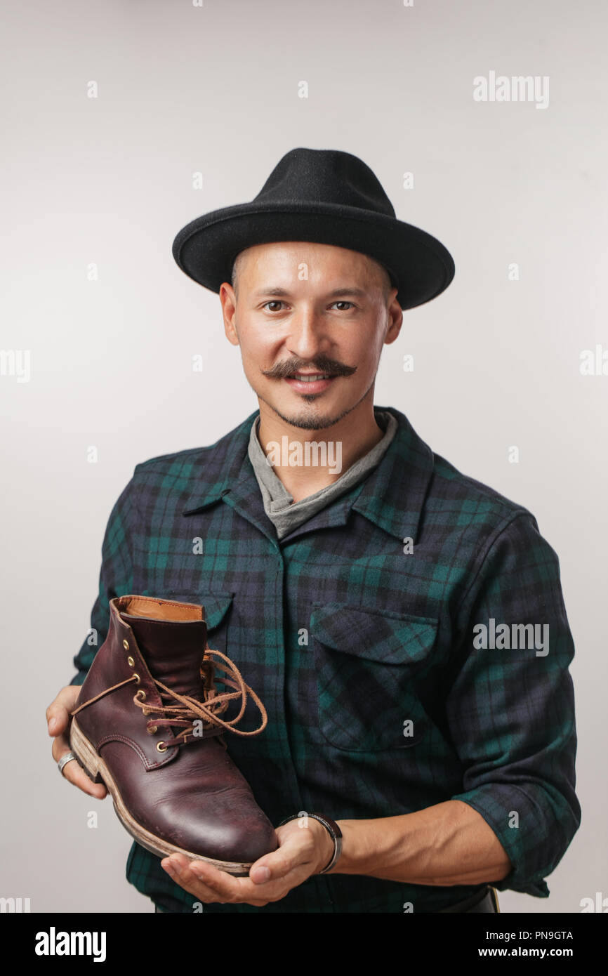 Photo of young cheerful shoemaker holding self made shoe isolated over ...