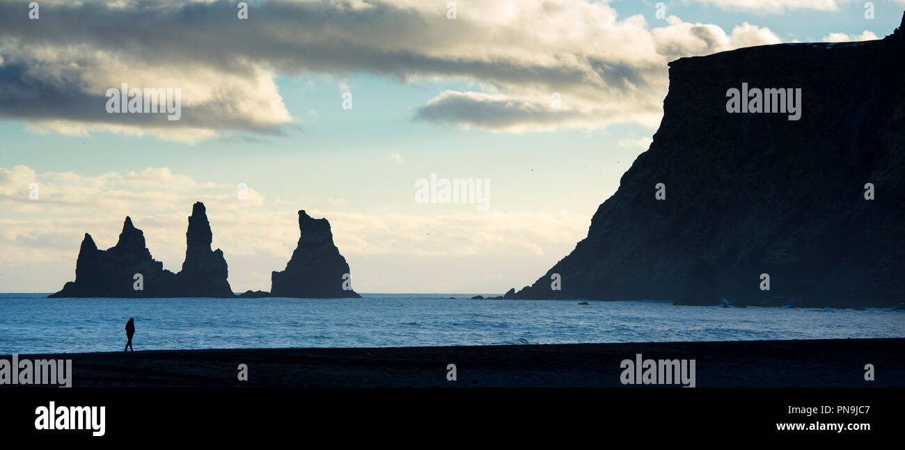 Tourist by Reynisdrangar basalt sea stacks (troll rocks) and black ...