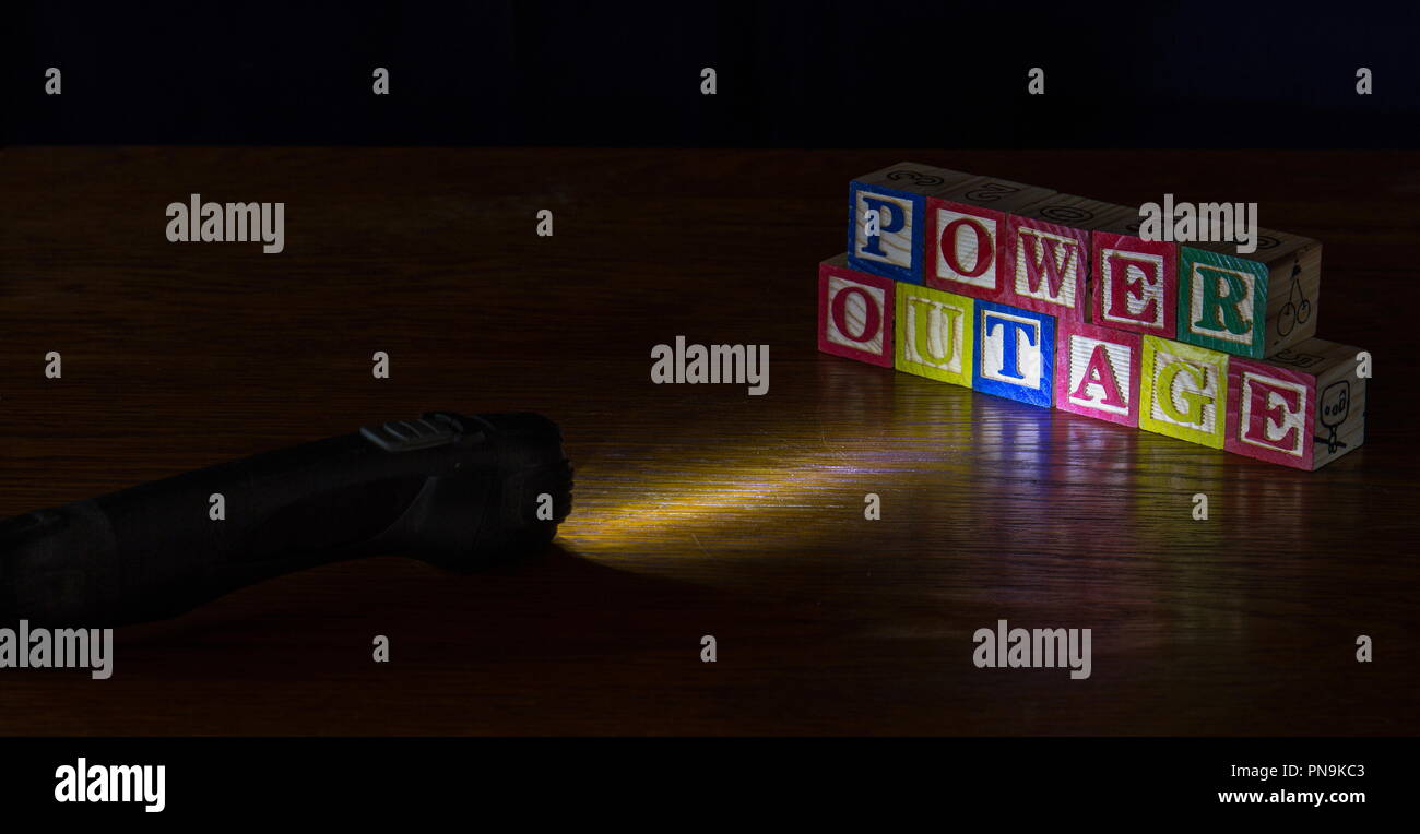 Torch light shining on the term power outage representing a conceptual ...