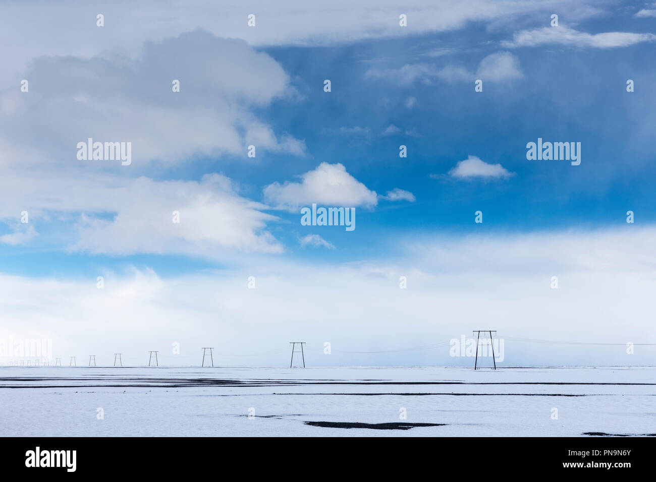 Marching sculptural row of electric power pylons carrying electricity ...