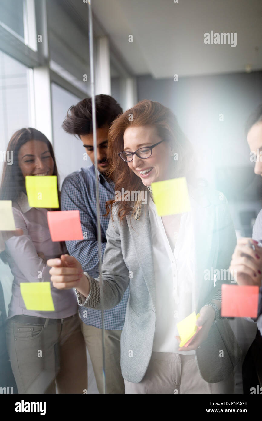 Creative business team looking at sticky notes on window Stock Photo ...