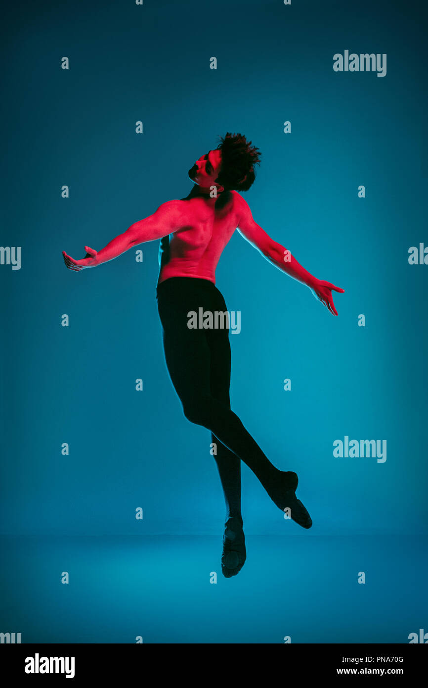 The male athletic ballet dancer performing dance on vivid blue ...