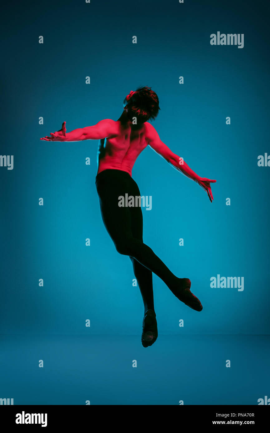 The male athletic ballet dancer performing dance on vivid blue ...