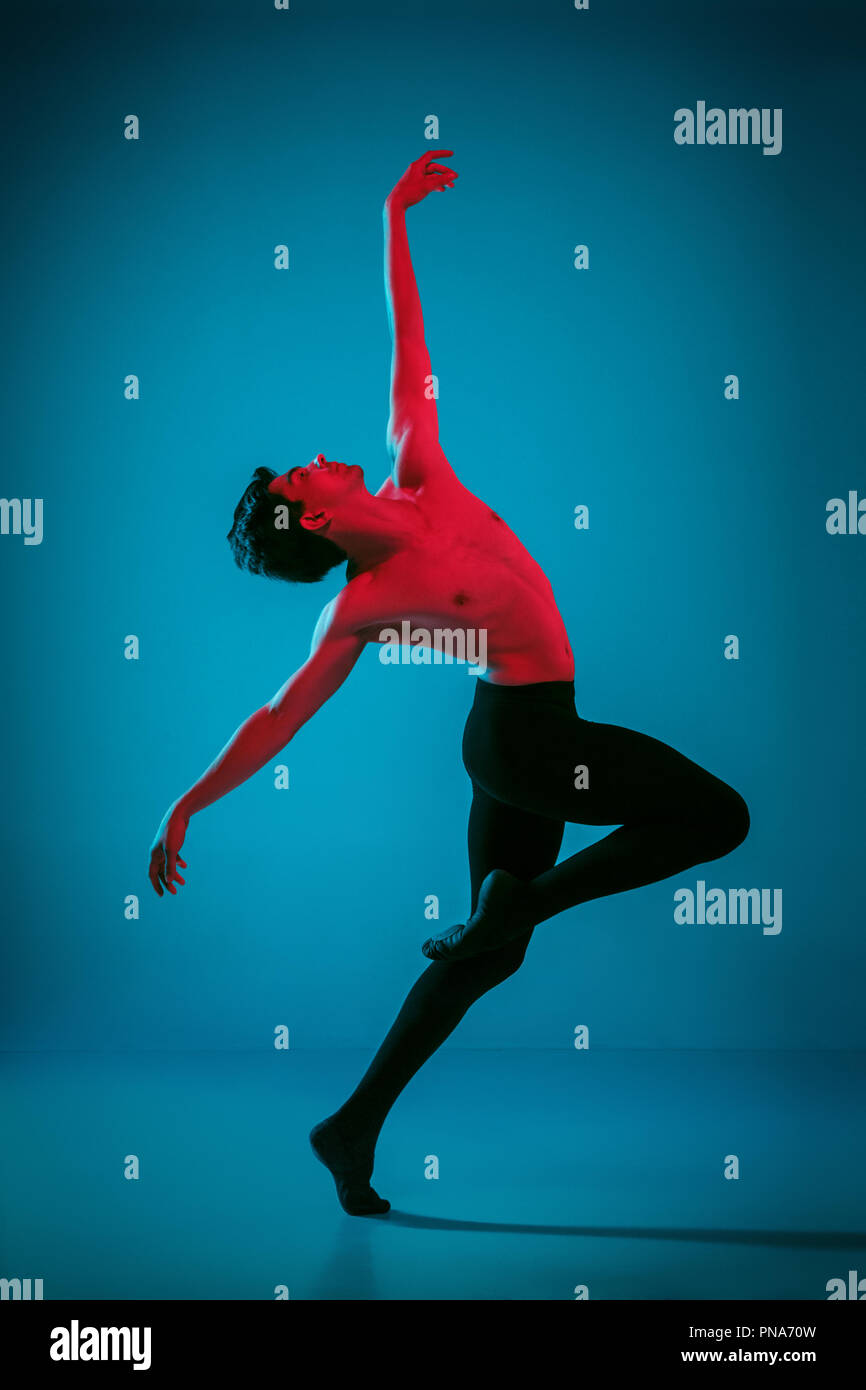 The male athletic ballet dancer performing dance on vivid blue ...