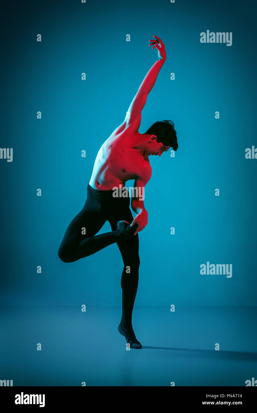 The male athletic ballet dancer performing dance on vivid blue ...