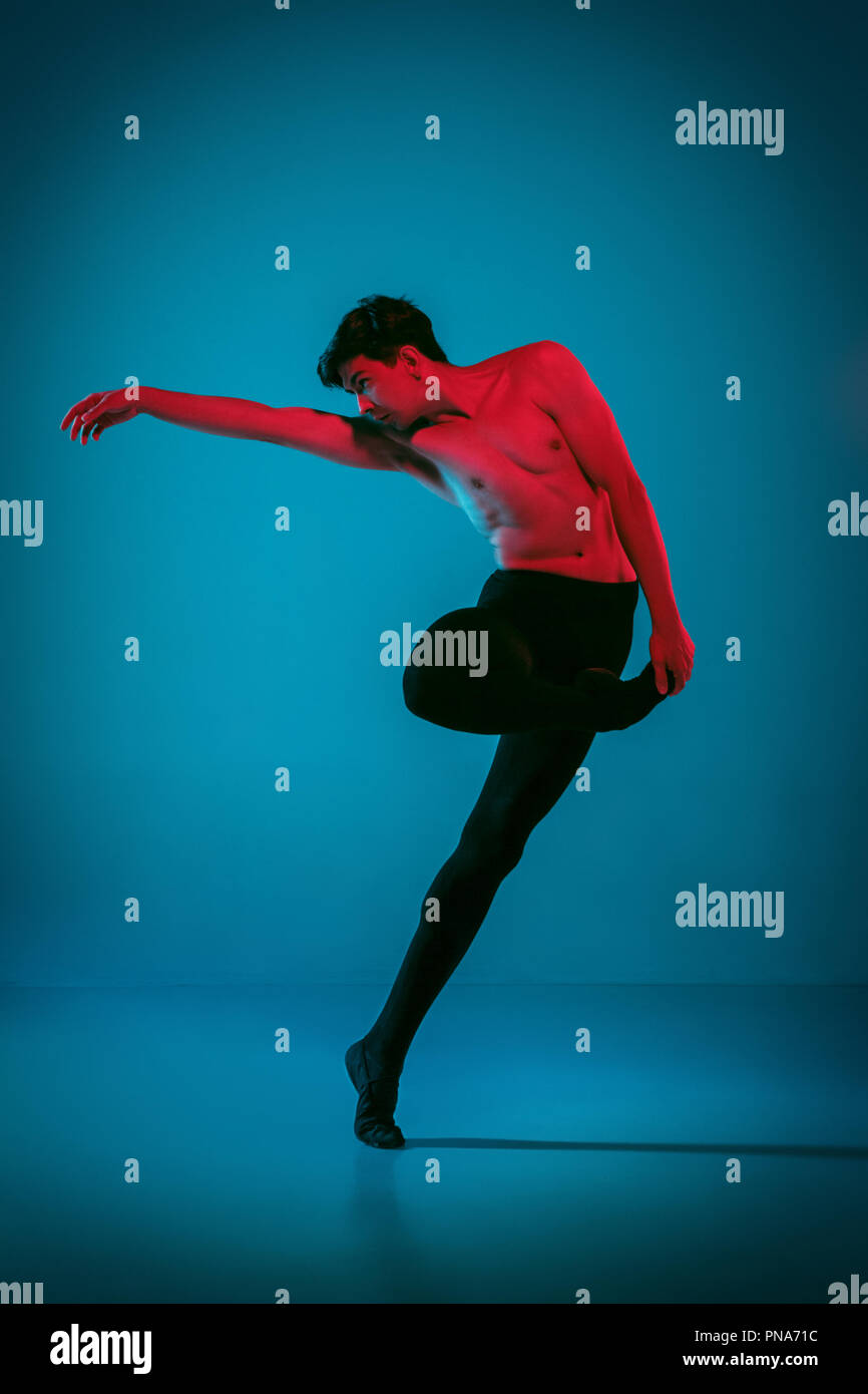 The male athletic ballet dancer performing dance on vivid blue ...