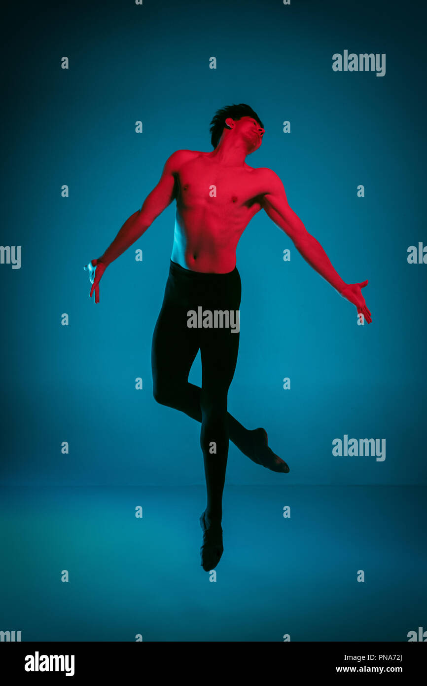 The male athletic ballet dancer performing dance on vivid blue ...