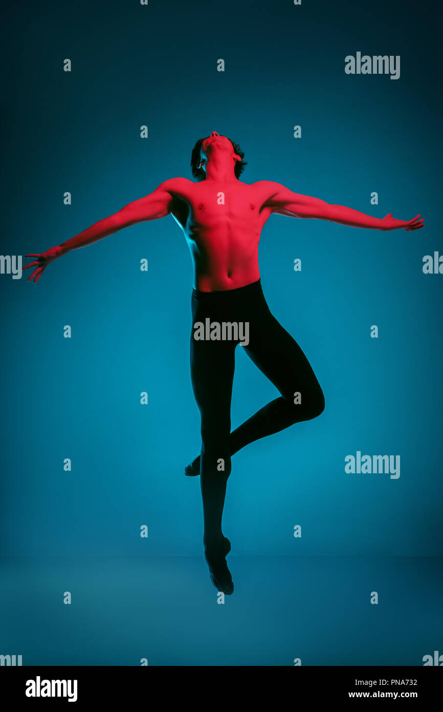 The male athletic ballet dancer performing dance on vivid blue ...