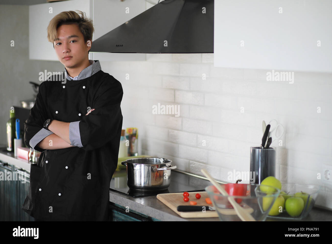 Asian cook in the kitchen prepares food in a cook suit Stock Photo - Alamy