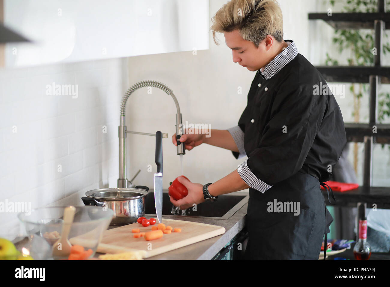 Asian cook in the kitchen prepares food in a cook suit Stock Photo - Alamy
