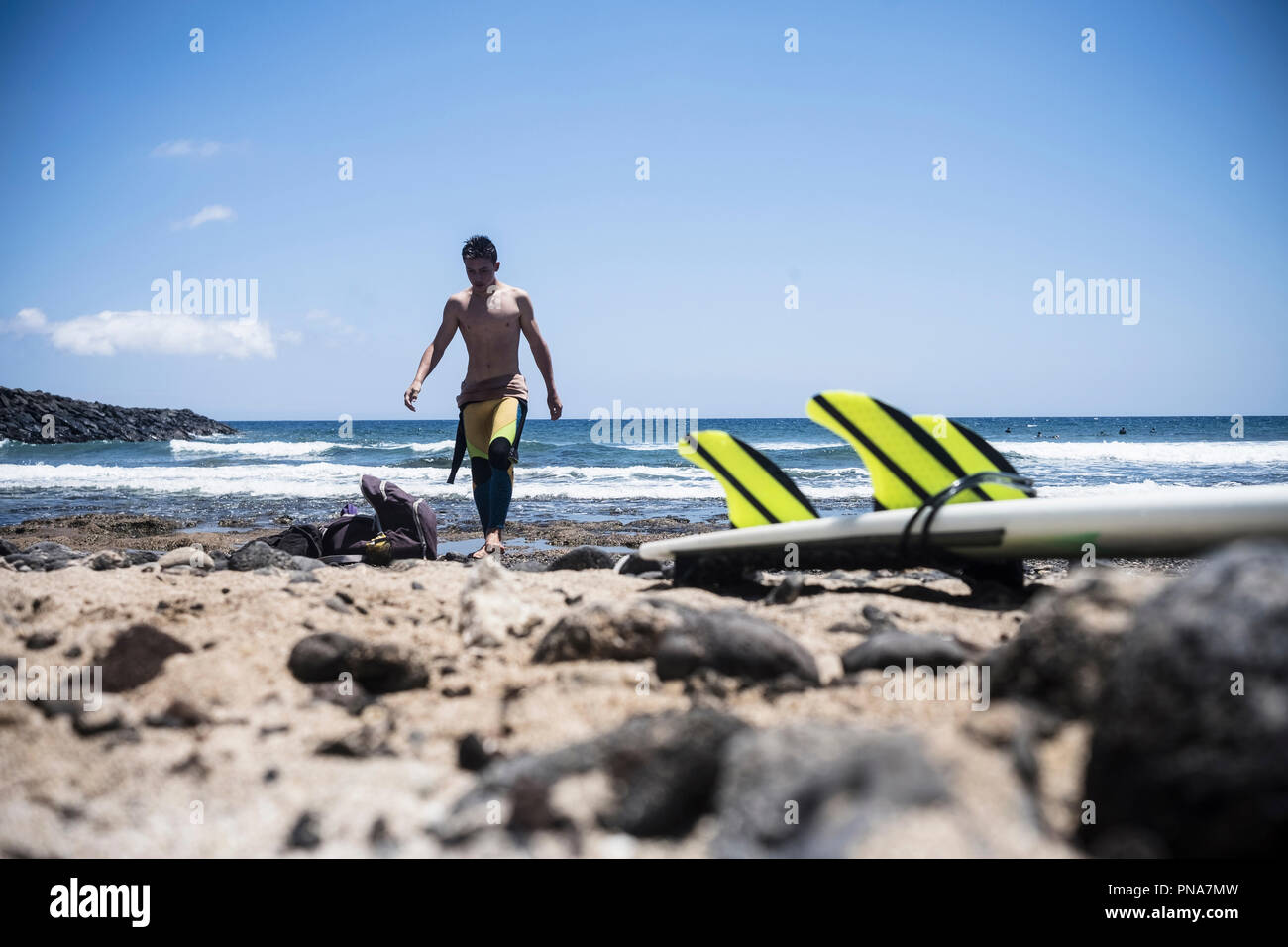 young cute teenager male surfer coming out the water after a surf ...