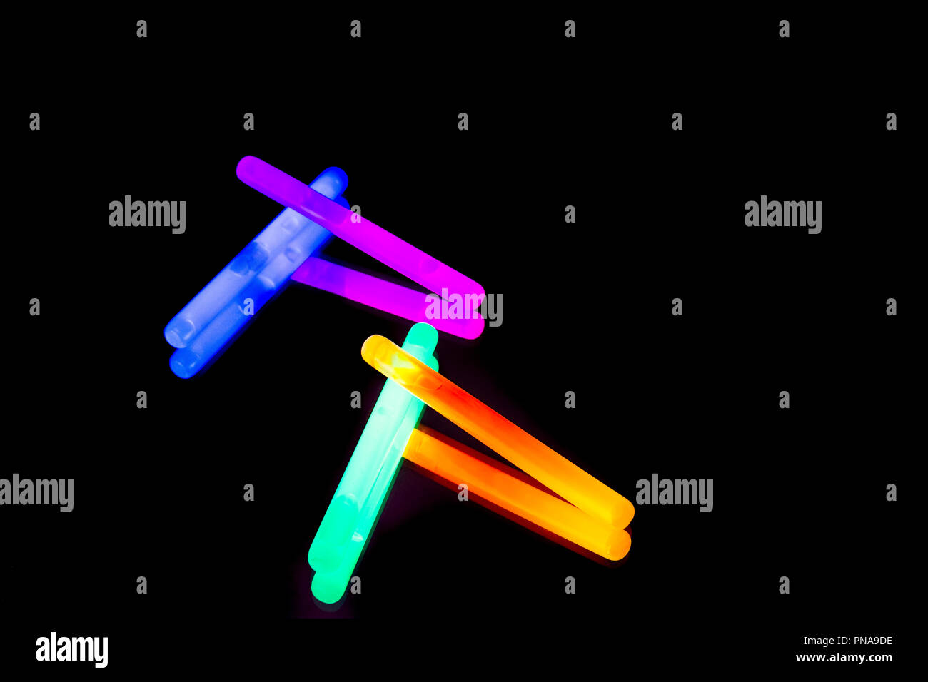 Colorful fluorescent light neon glow stick on mirror reflection black ...