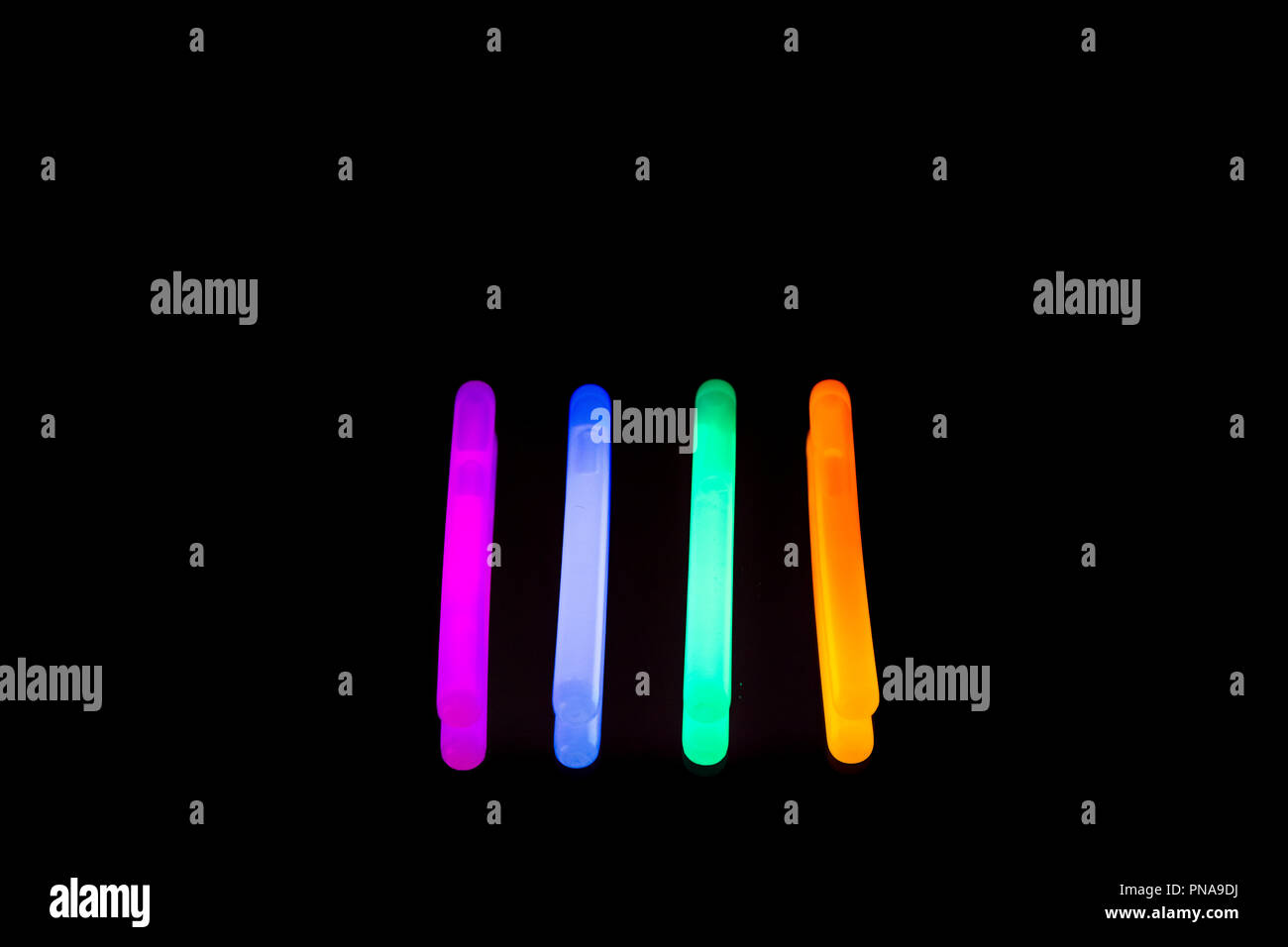 Colorful fluorescent light neon glow stick on mirror reflection black ...