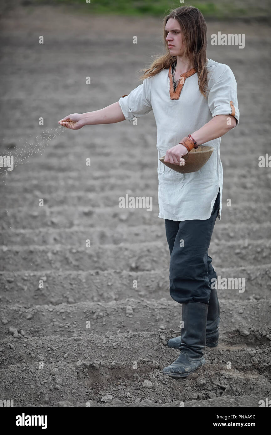 A young peasant sows the field with grain Stock Photo - Alamy