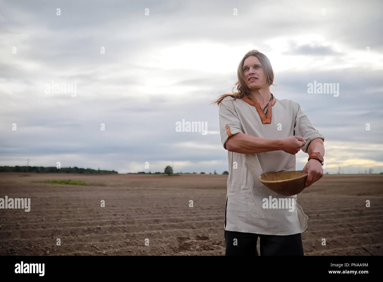 A young peasant sows the field with grain Stock Photo - Alamy