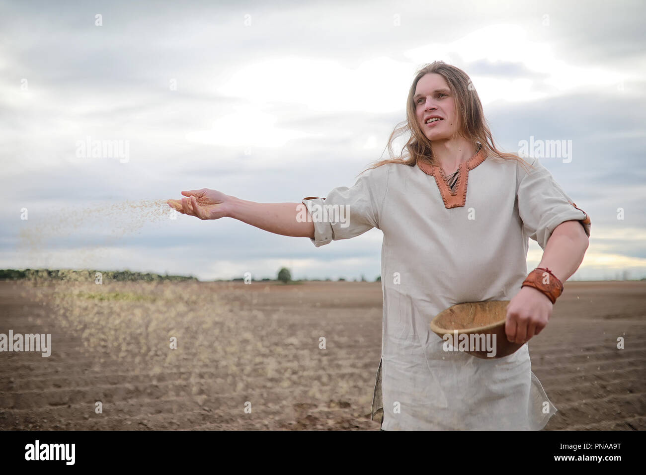 A young peasant sows the field with grain Stock Photo - Alamy
