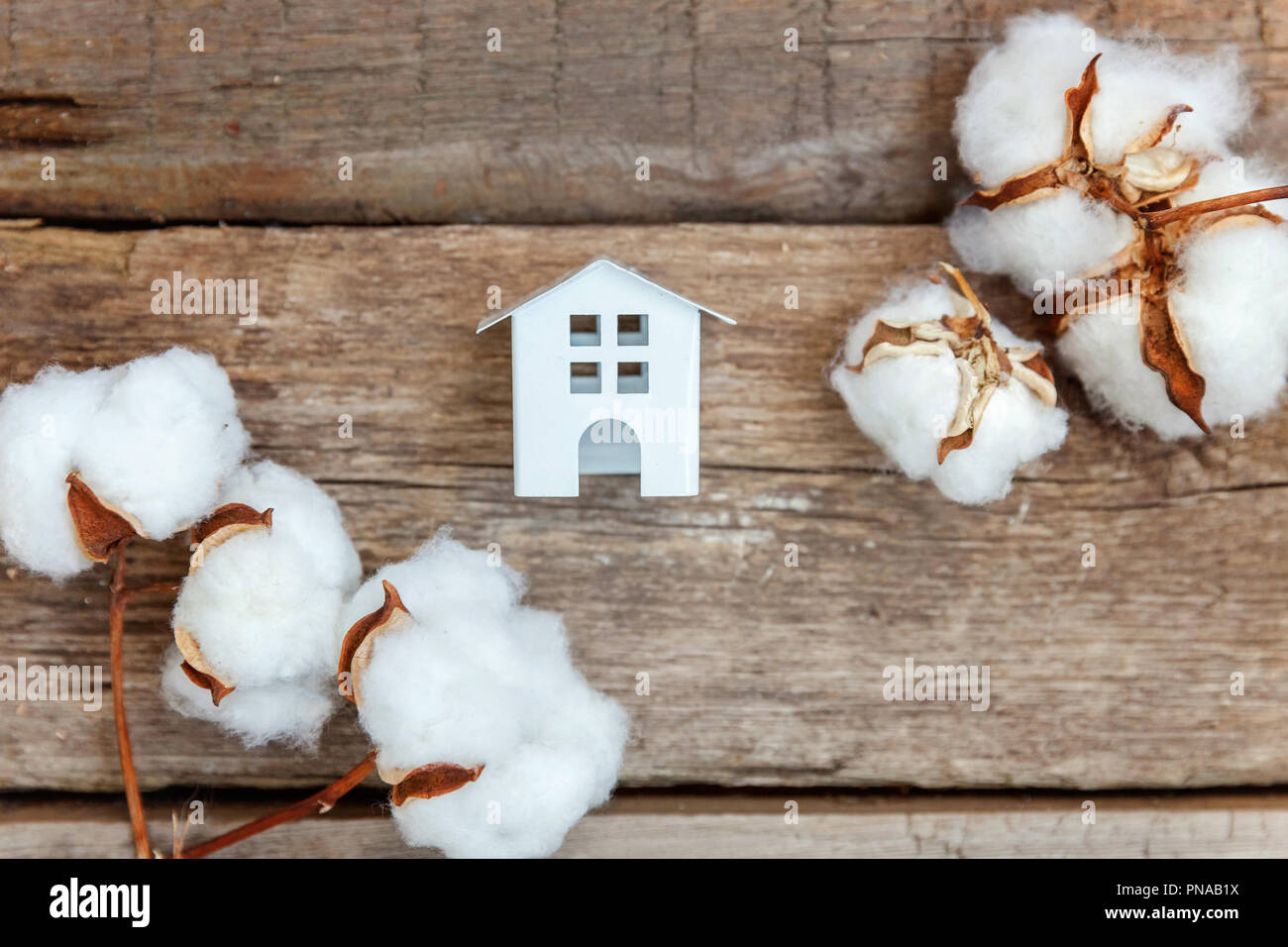 Miniature white toy house with cotton flowers on a rustic old vintage ...