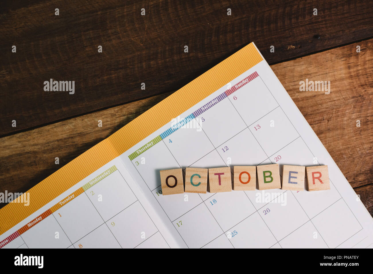 closeup of OCTOBER alphabet tile on planner book calendar on wooden ...