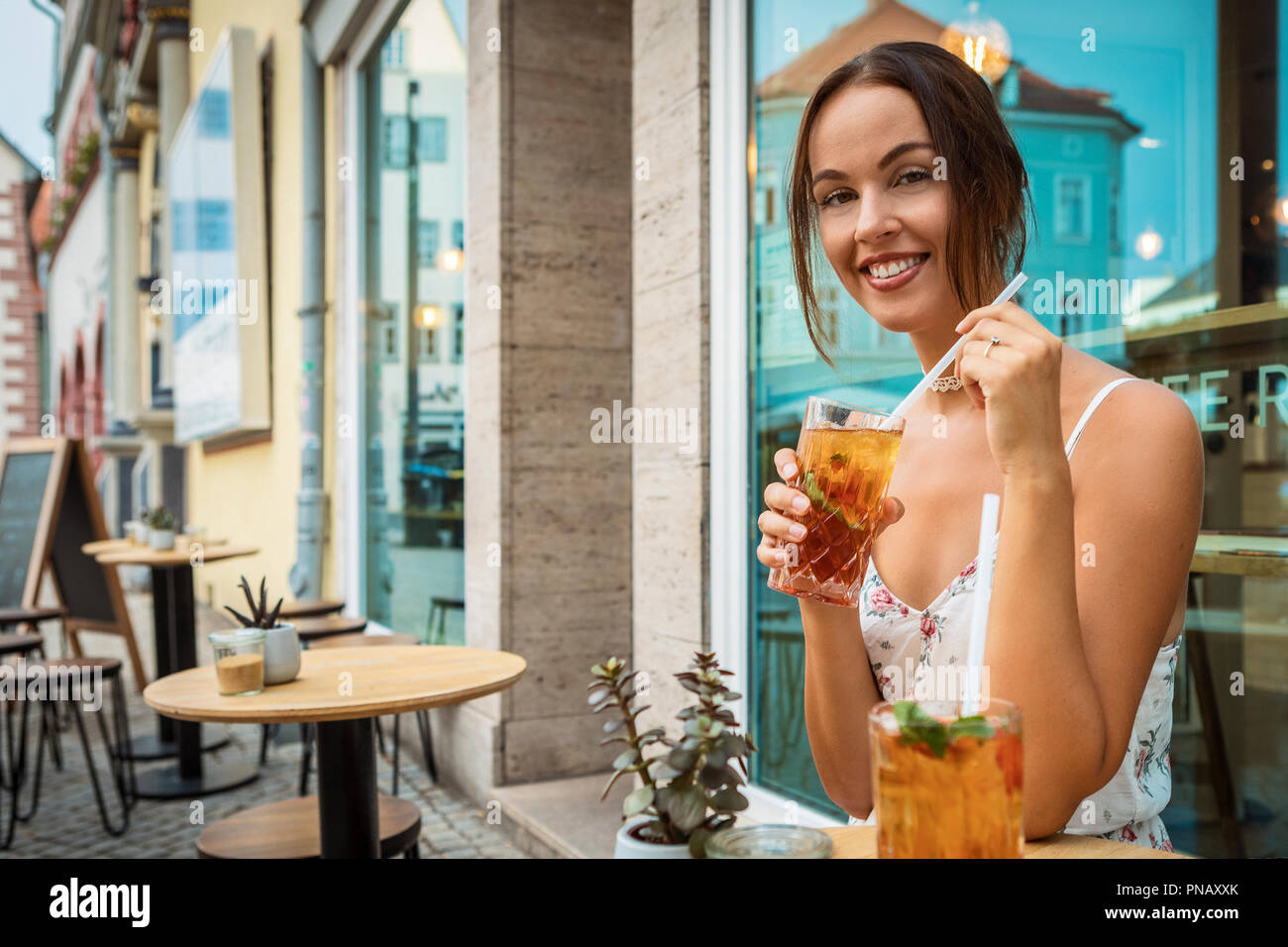 Young brunette woman having ice tea at a café Stock Photo - Alamy