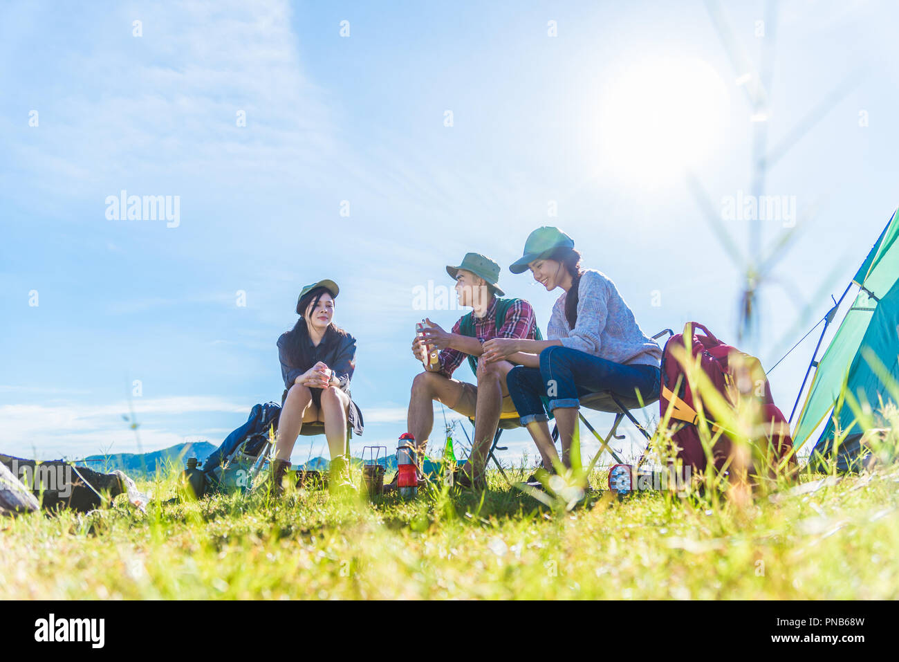 Group of travelers camping and doing picnic in meadow field foreground ...