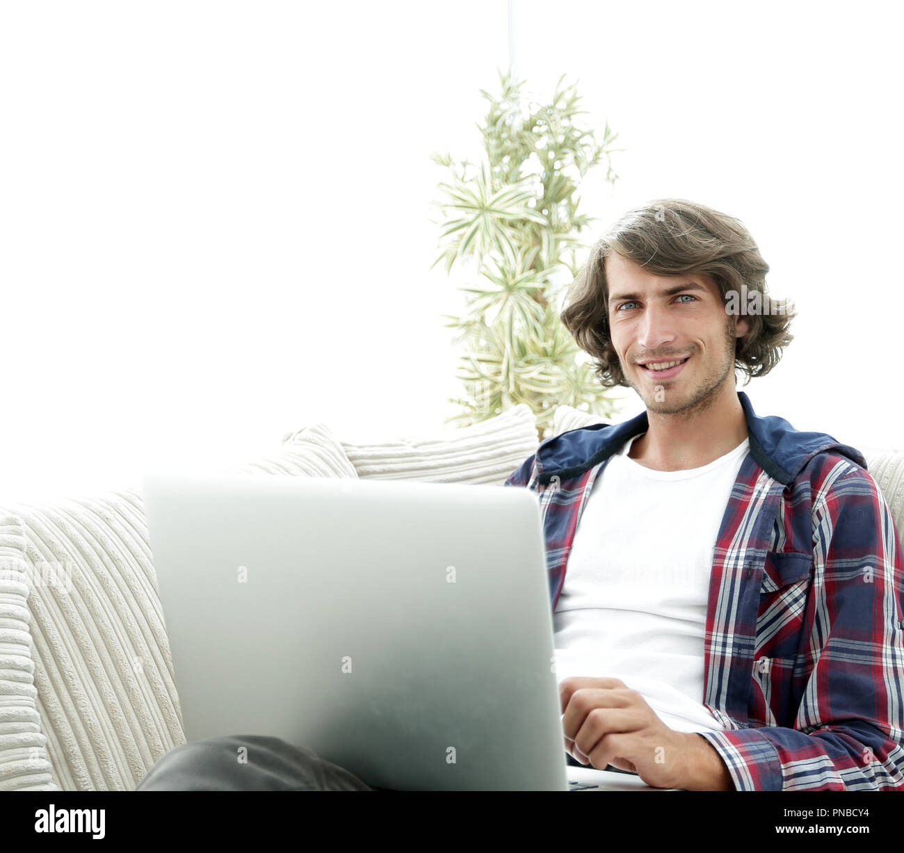 Portrait of a young man with a laptop sitting in a chair Stock Photo ...