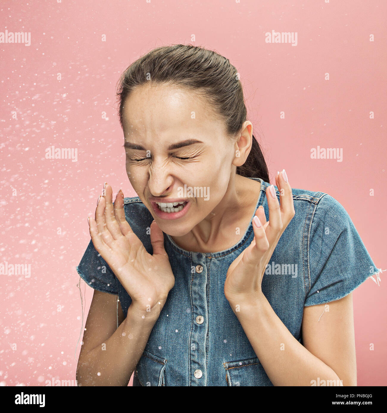 Young funny woman sneezing with spray and small drops, studio portrait ...