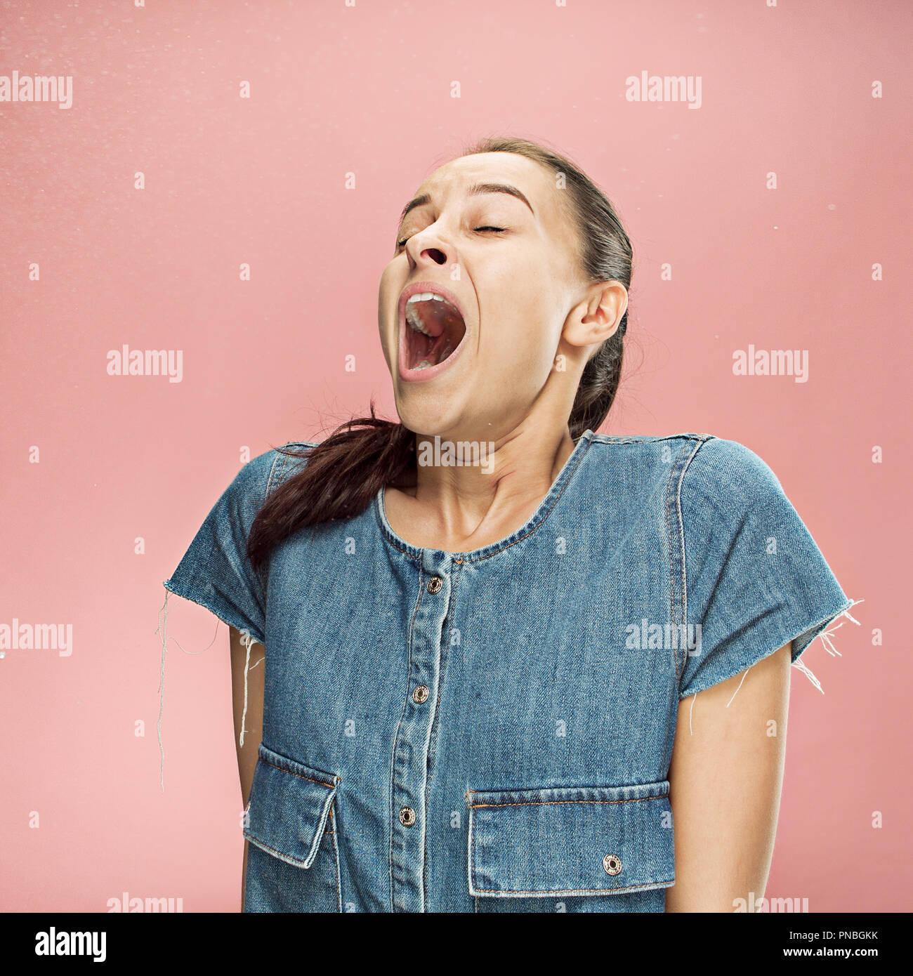 Young funny woman sneezing with spray and small drops, studio portrait ...