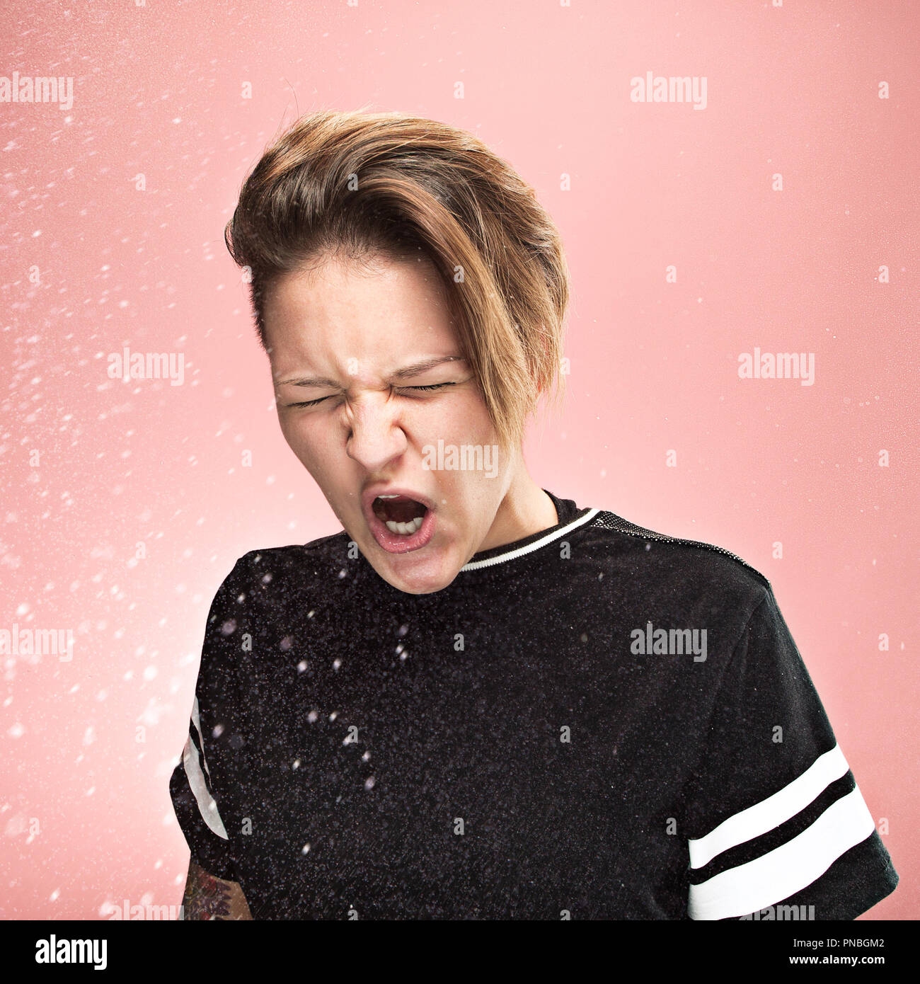 Young funny woman sneezing with spray and small drops, studio portrait ...