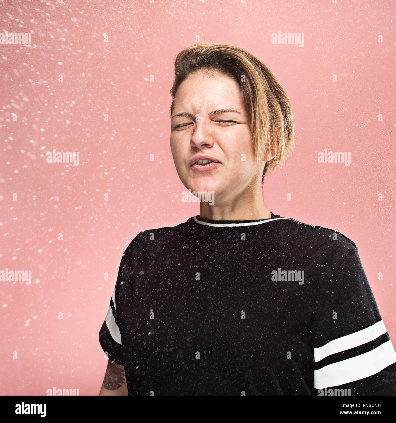 Young funny woman sneezing with spray and small drops, studio portrait ...