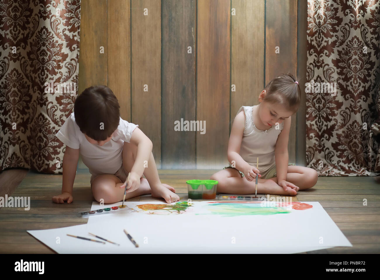 Little children paint on a large sheet of paper Stock Photo - Alamy