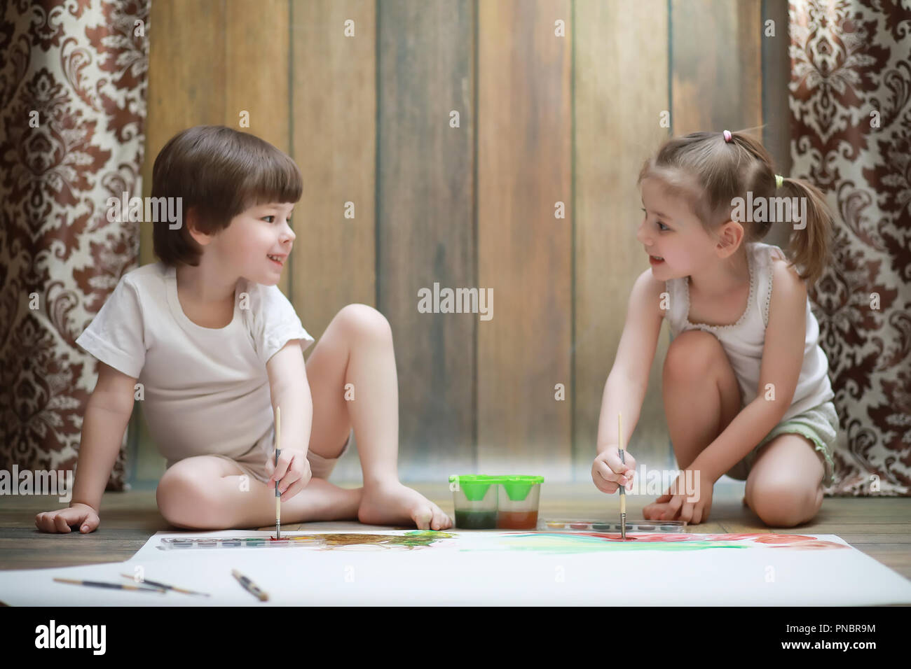 Little children paint on a large sheet of paper Stock Photo - Alamy